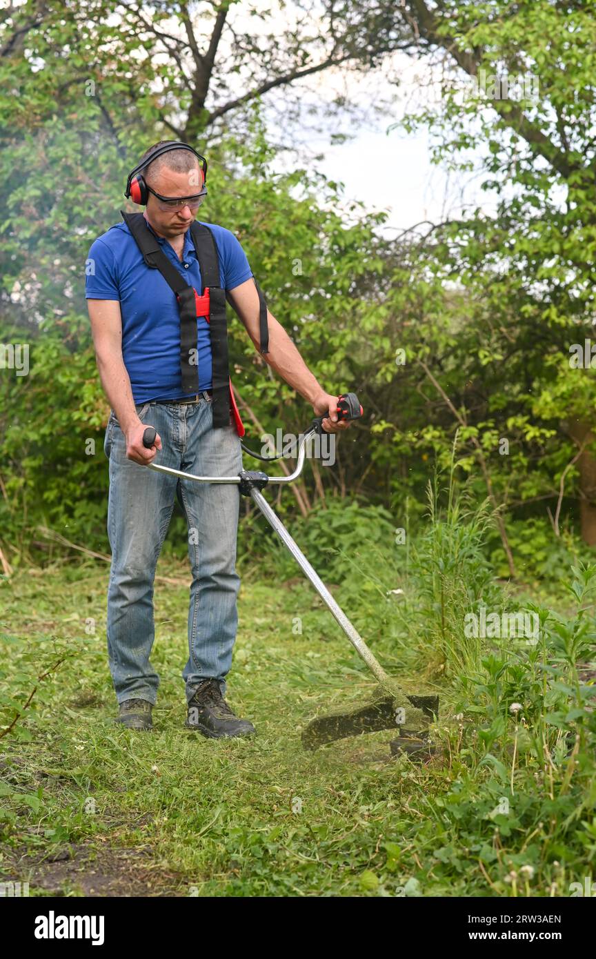 Man mowing tall grass. Process of lawn trimming with hand mower Stock ...