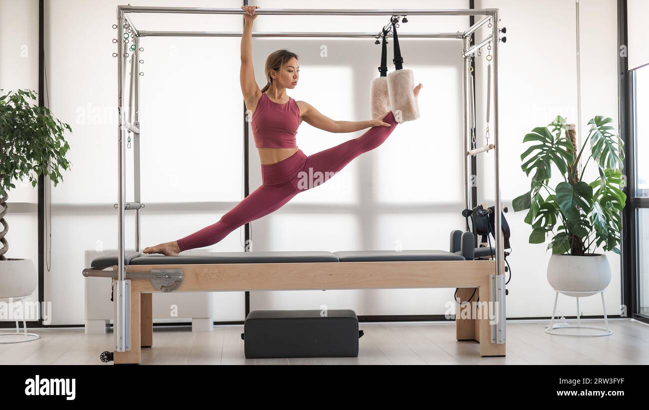 Beautiful asian woman doing splits on a reformer Stock Photo - Alamy