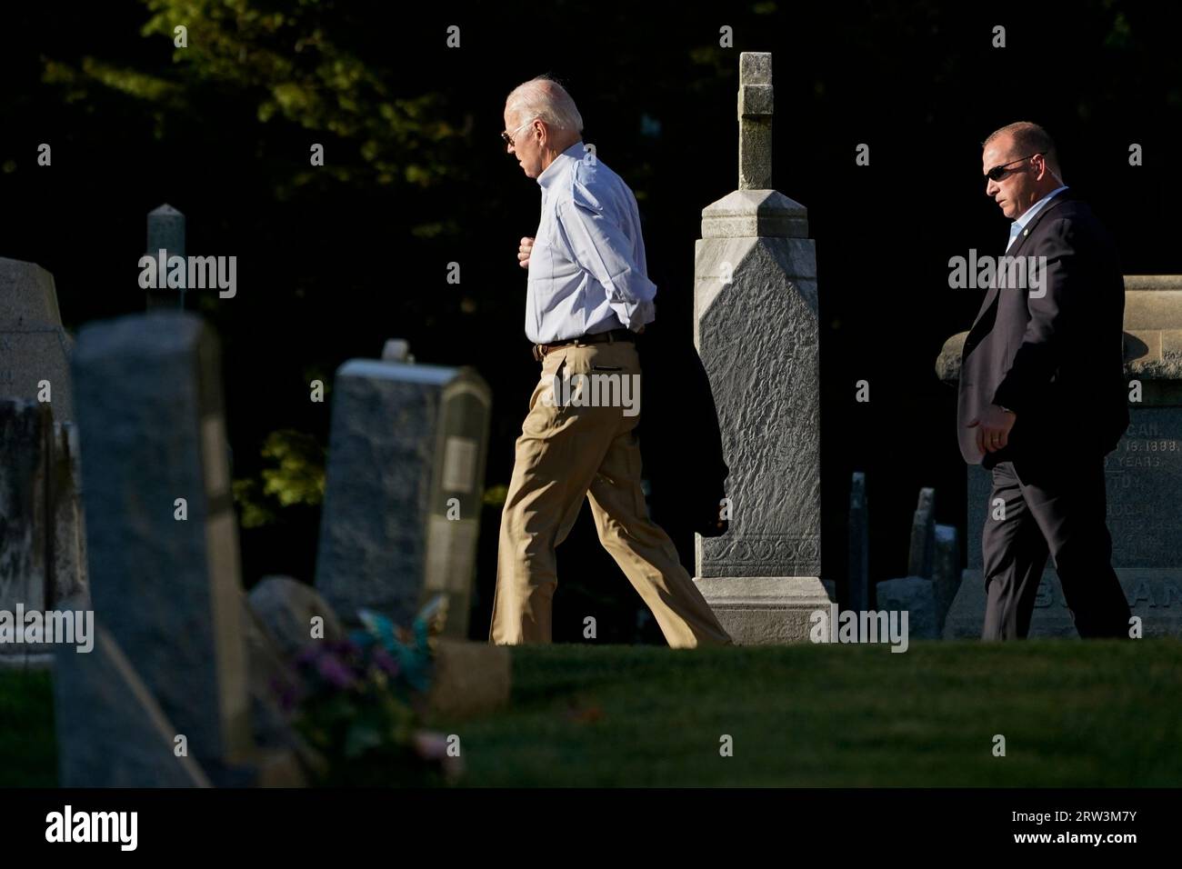 President Joe Biden puts his jacket on while walking between tombstones ...