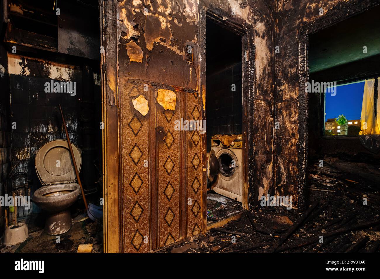 Burnt house interior. Fused remains of furniture and washing machine ...
