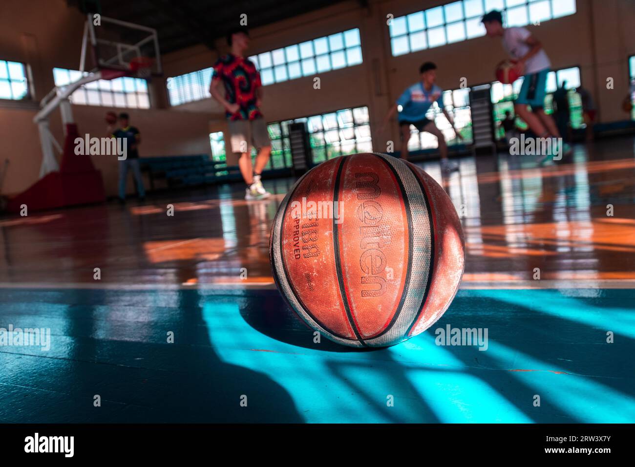 An image of a basketball situated on a gym court in focus with a ...