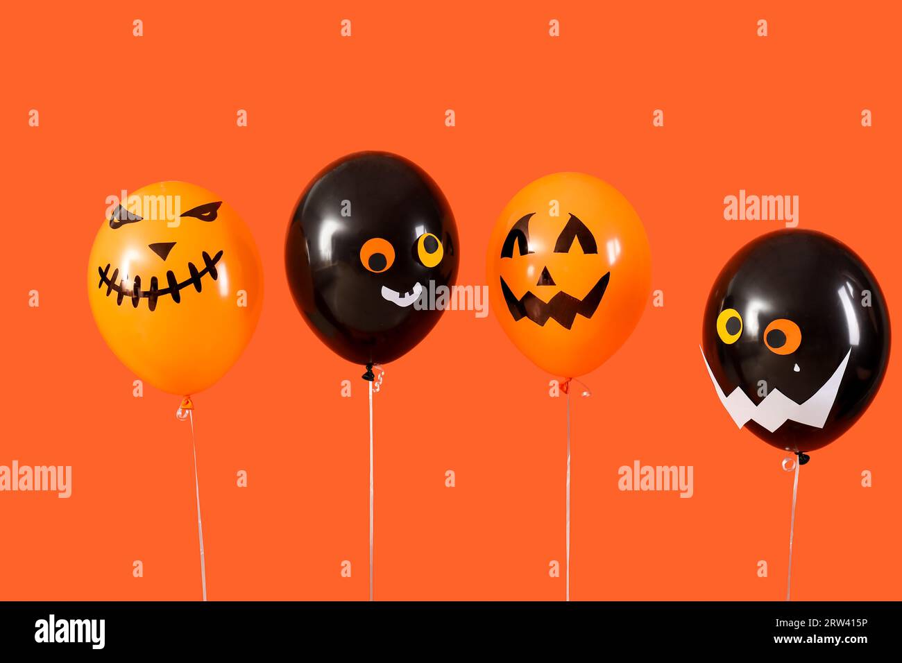 Different creepy Halloween balloons on orange background Stock Photo ...