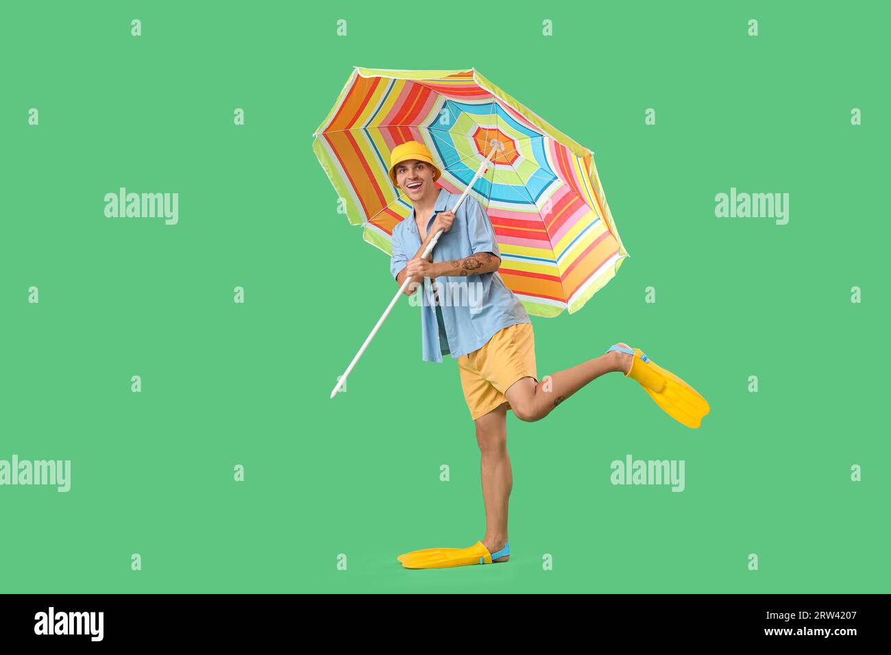 Happy young man in flippers with umbrella on green background Stock ...