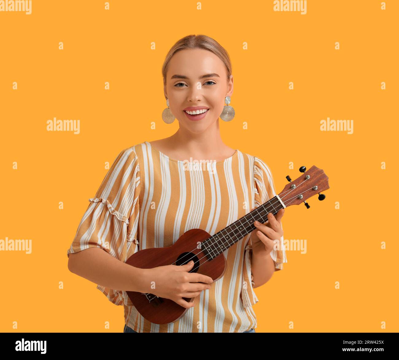 Pretty young woman with ukulele on orange background Stock Photo - Alamy
