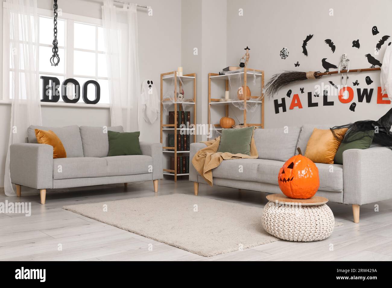 Interior of light living room decorated for Halloween with sofas and shelf units Stock Photo - Alamy