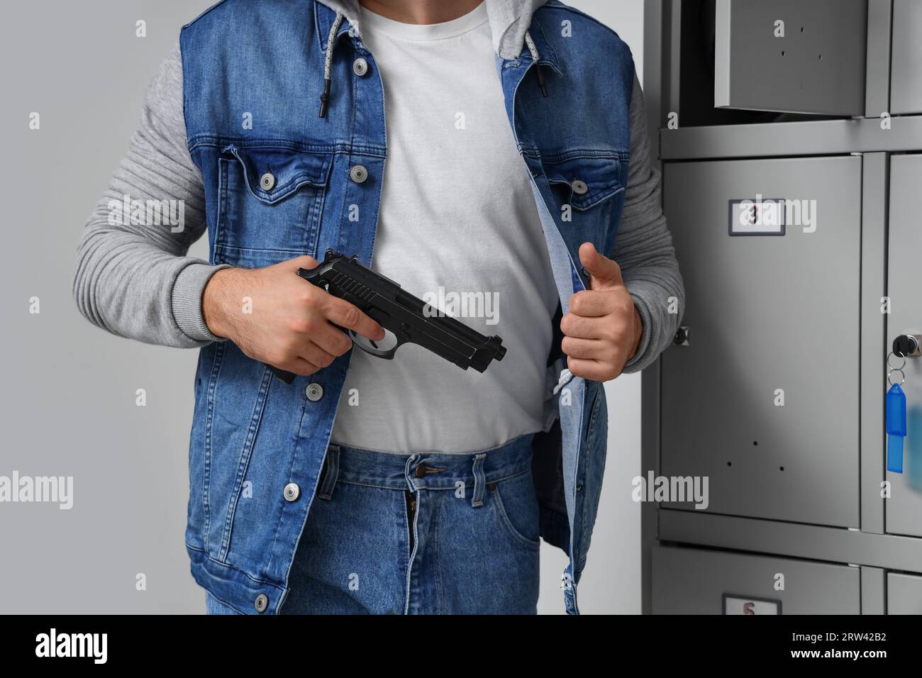 Male student with gun near locker, closeup. School shooting concept ...