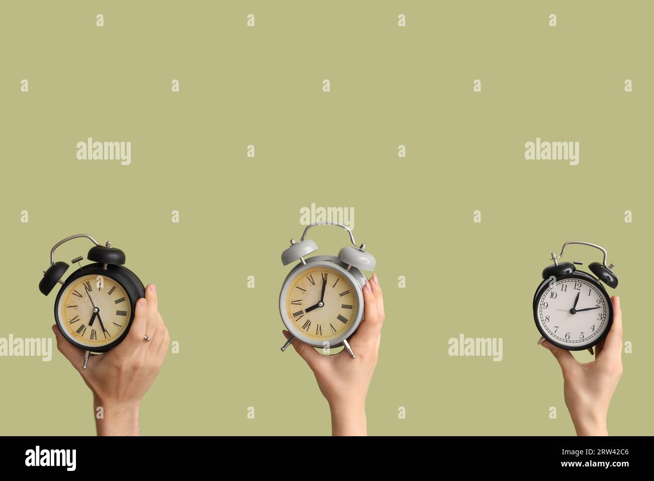 Hands holding different alarm clocks on green background Stock Photo ...