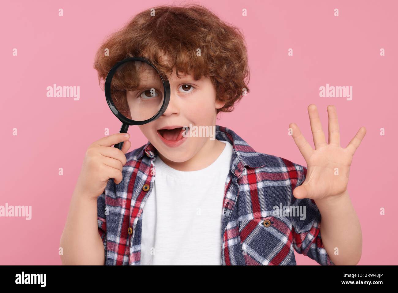 Cute little boy looking through magnifier glass on pink background Stock Photo - Alamy