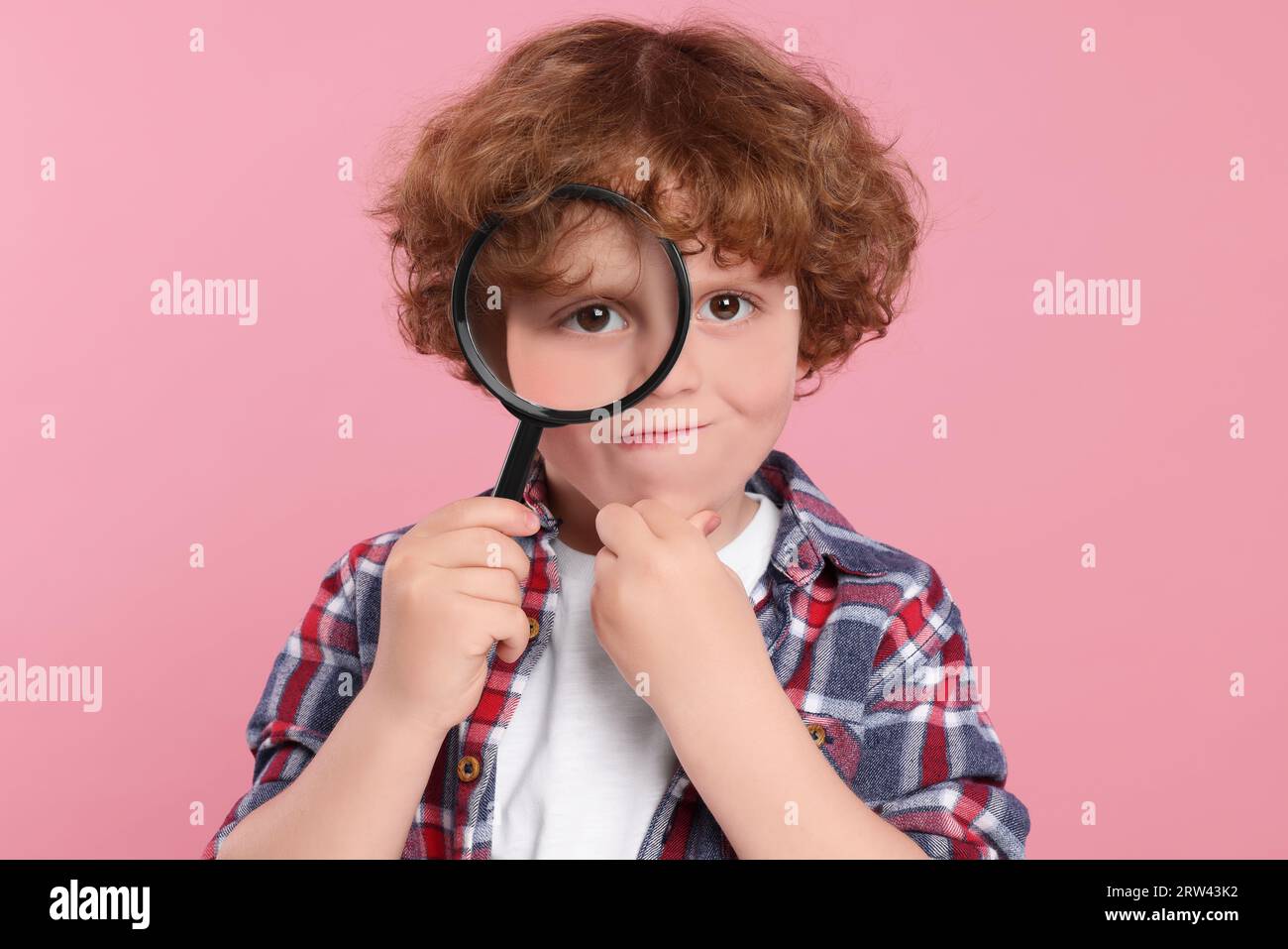 Cute little boy looking through magnifier glass on pink background Stock Photo - Alamy
