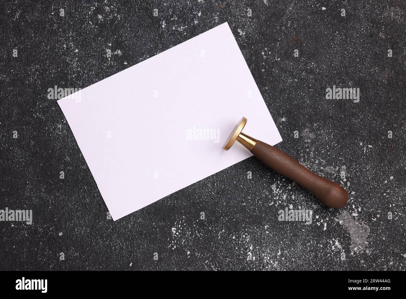 One stamp tool and sheet of paper on dark textured background, top view ...