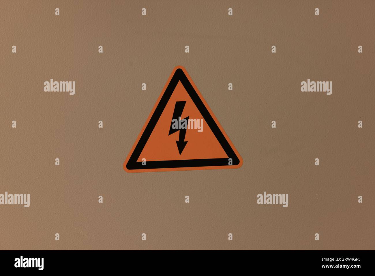 yellow triangular electrical hazard and warning sign on a chain-link ...