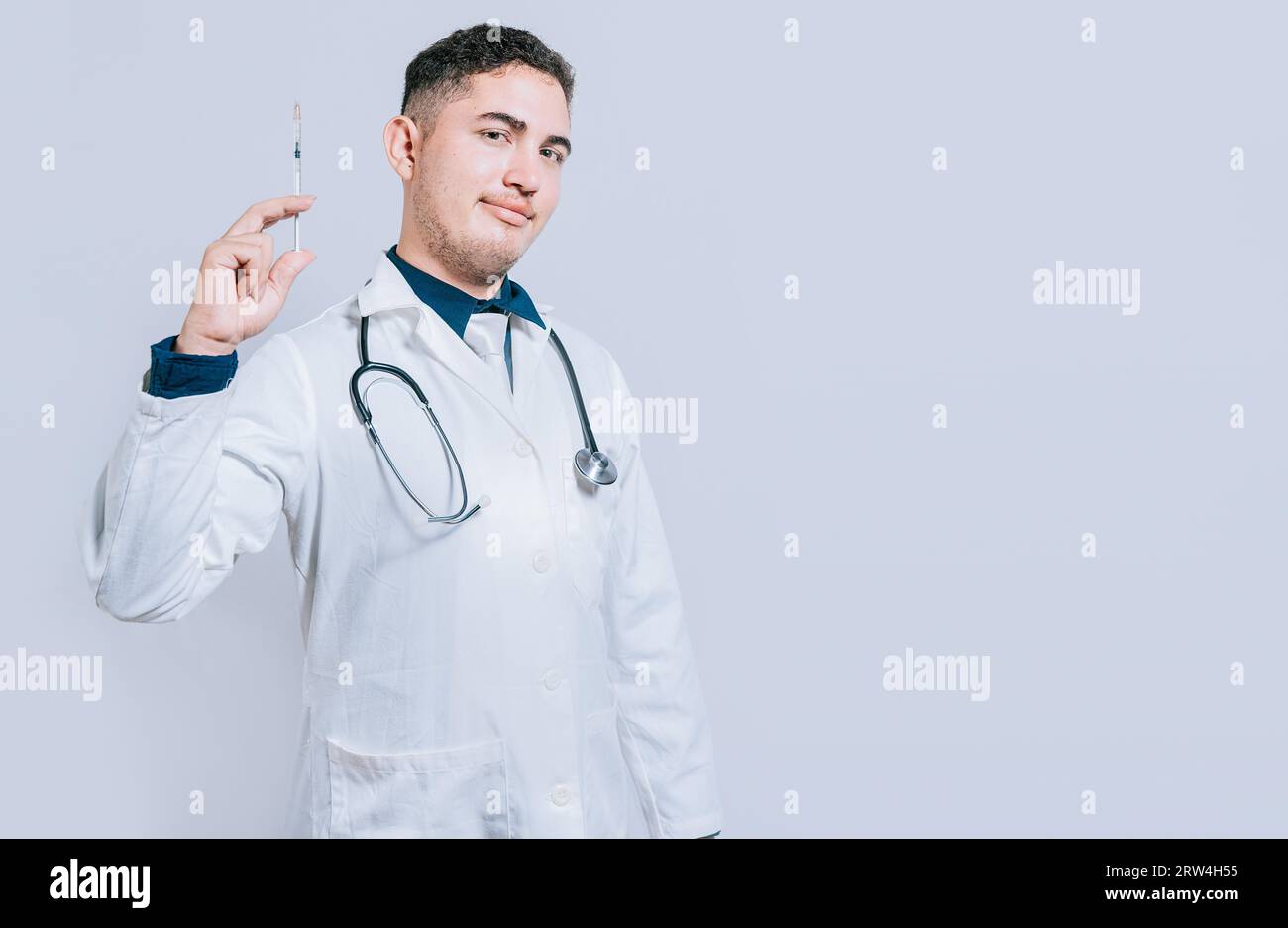 Friendly doctor holding a syringe isolated. Smiling doctor showing a ...
