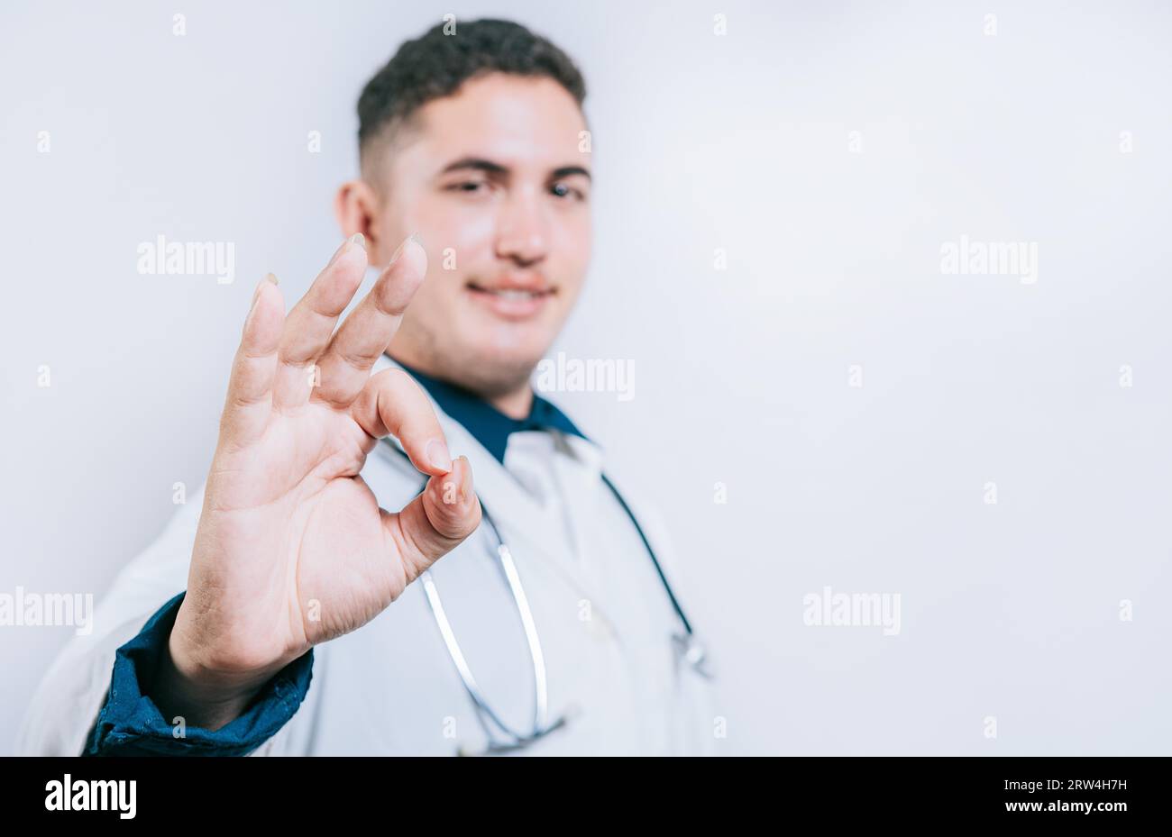 Cheerful doctor gesturing approval isolated. Handsome latin doctor ...