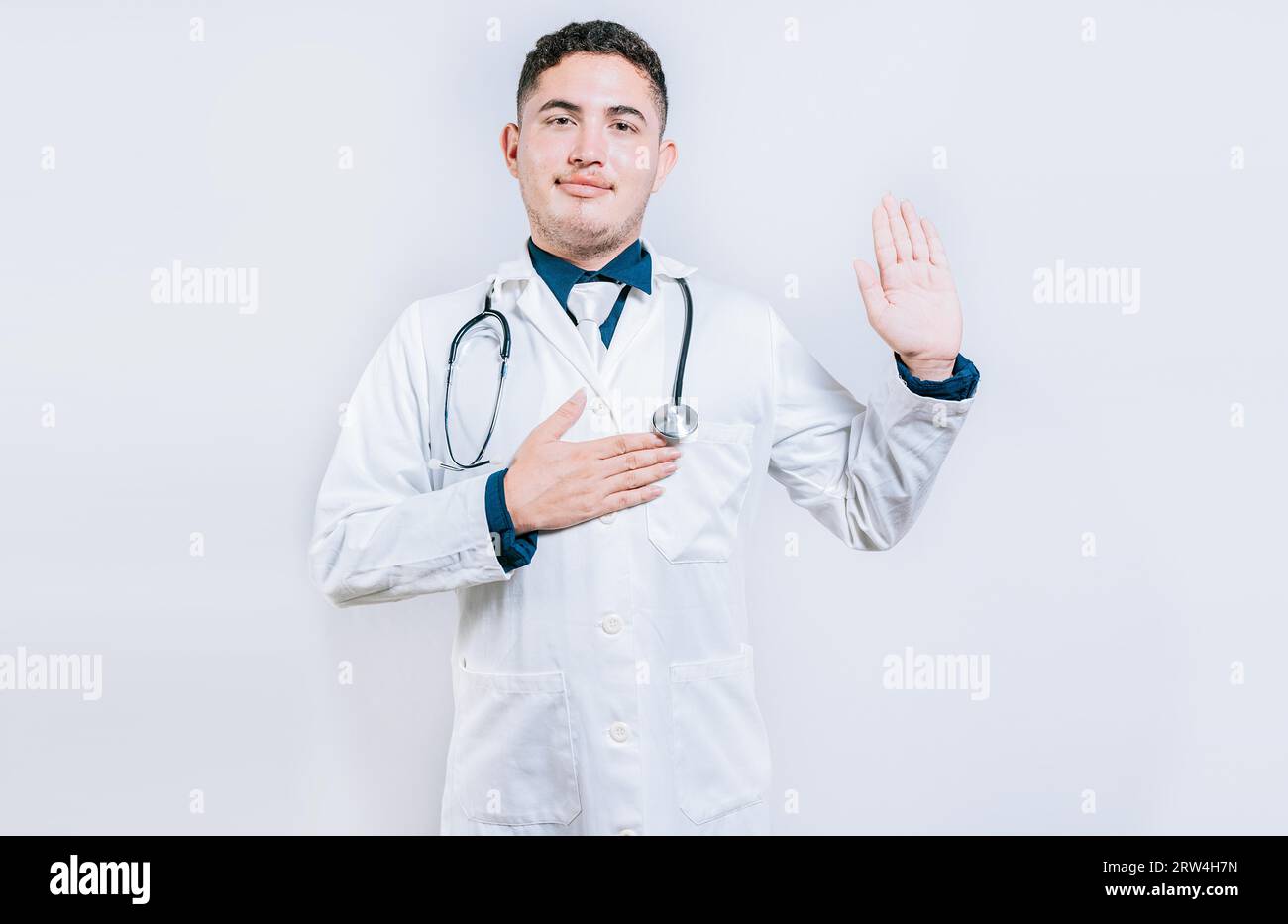 Young doctor raising hand and swearing isolated. handsome doctor making ...