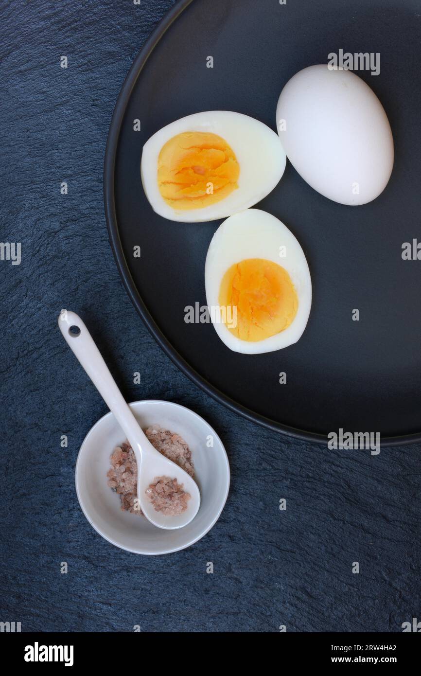Boiled egg, halved, and spoon with natural salt Stock Photo - Alamy