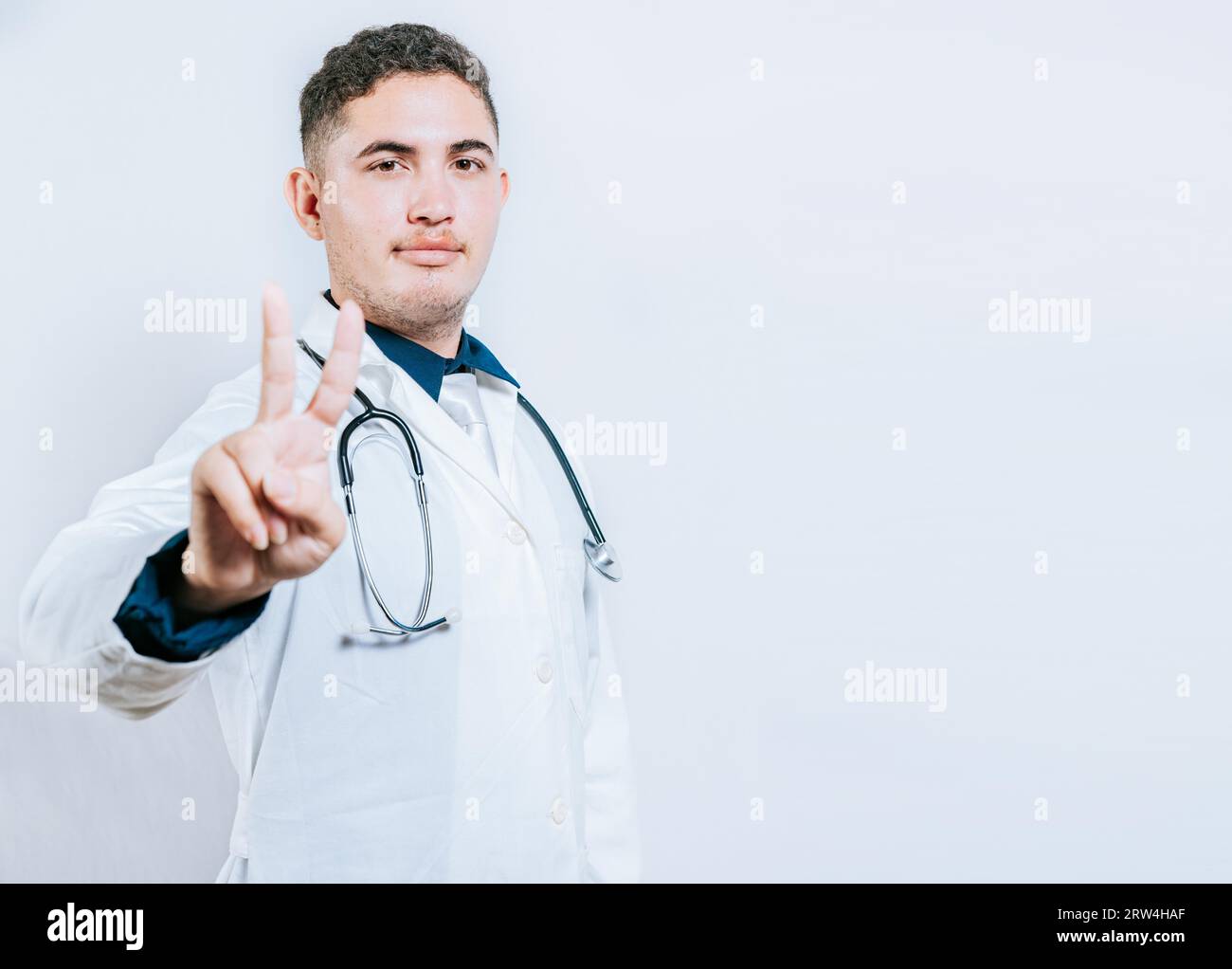 Latin doctor counting number two isolated. Smiling young doctor ...