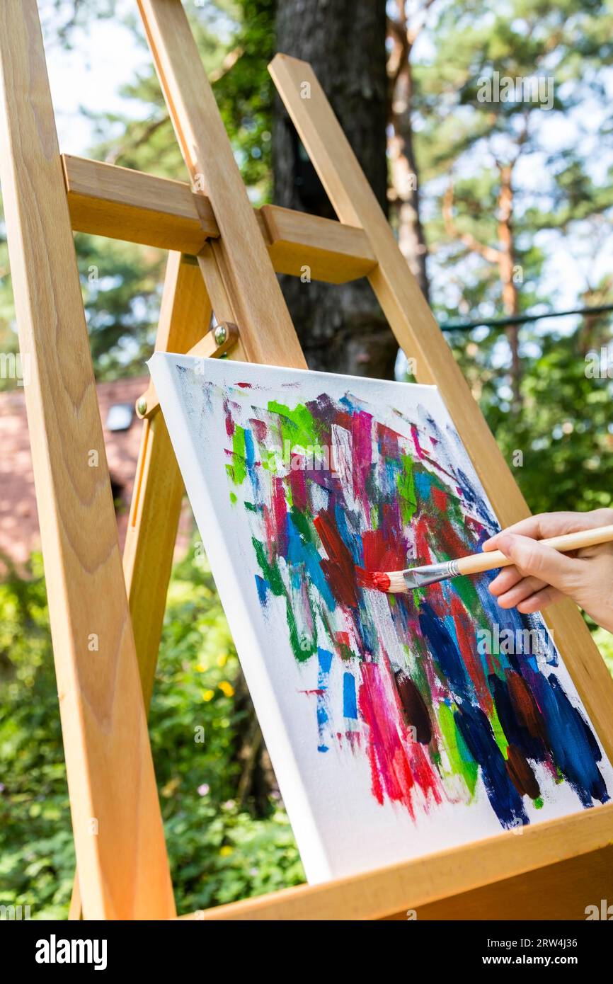 Painting with acrylic colours on an easel in a garden, painting with ...