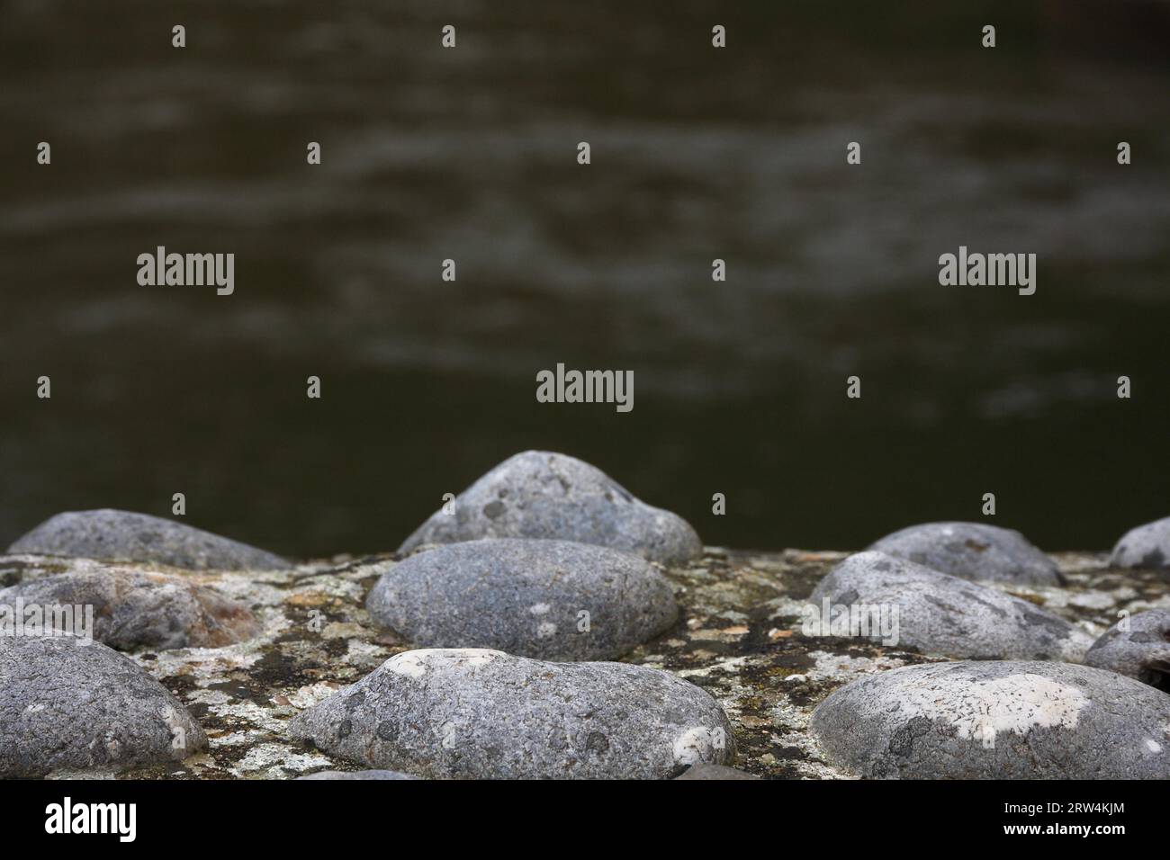 The edge of the river bank fixed with grey stones, background river ...
