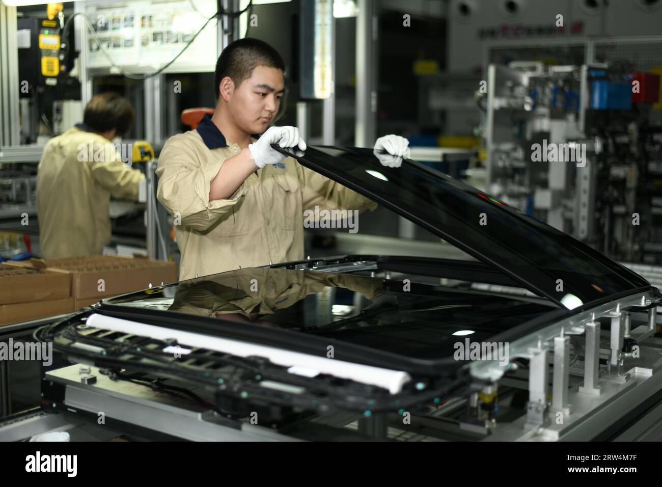 A worker produces sunroof glass for new energy vehicles on an ...