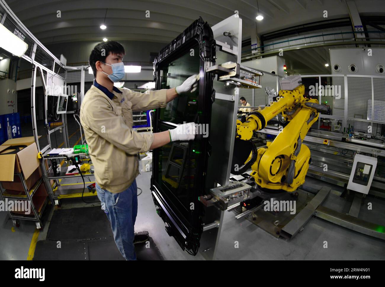 A worker produces sunroof glass for new energy vehicles on an ...