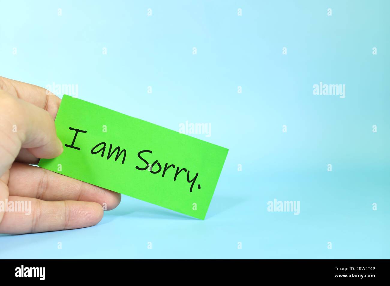 I am sorry message concept. Hand holding a bright yellow paper with ...