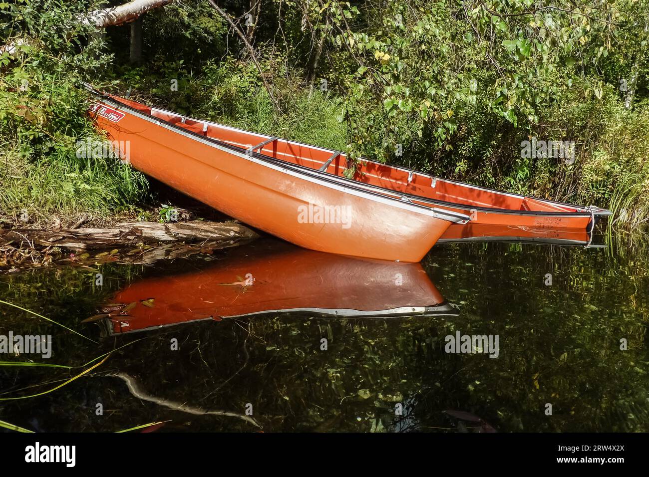Two canoes at a lakeshore of X Lake reflecting the late afternoon sun ...