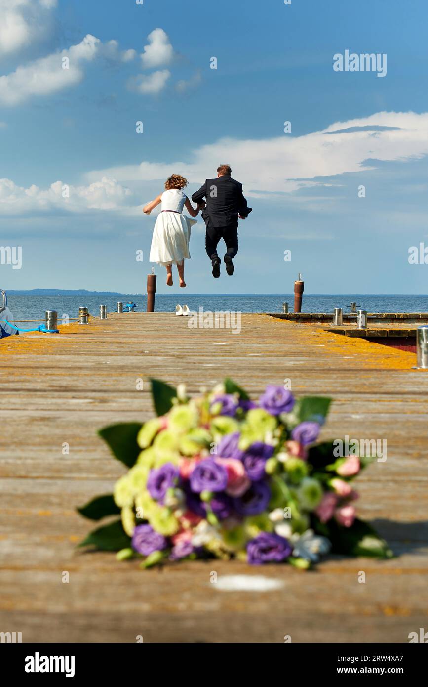 Wedding couple jumping in water Stock Photo - Alamy