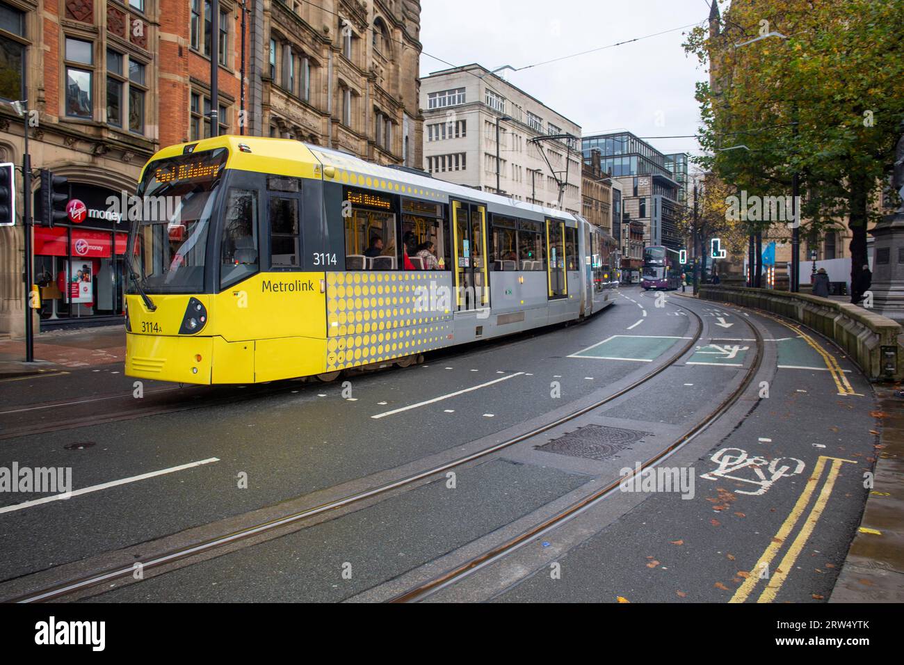 A yellow Metrolink tram passes through the city centre. Manchester ...