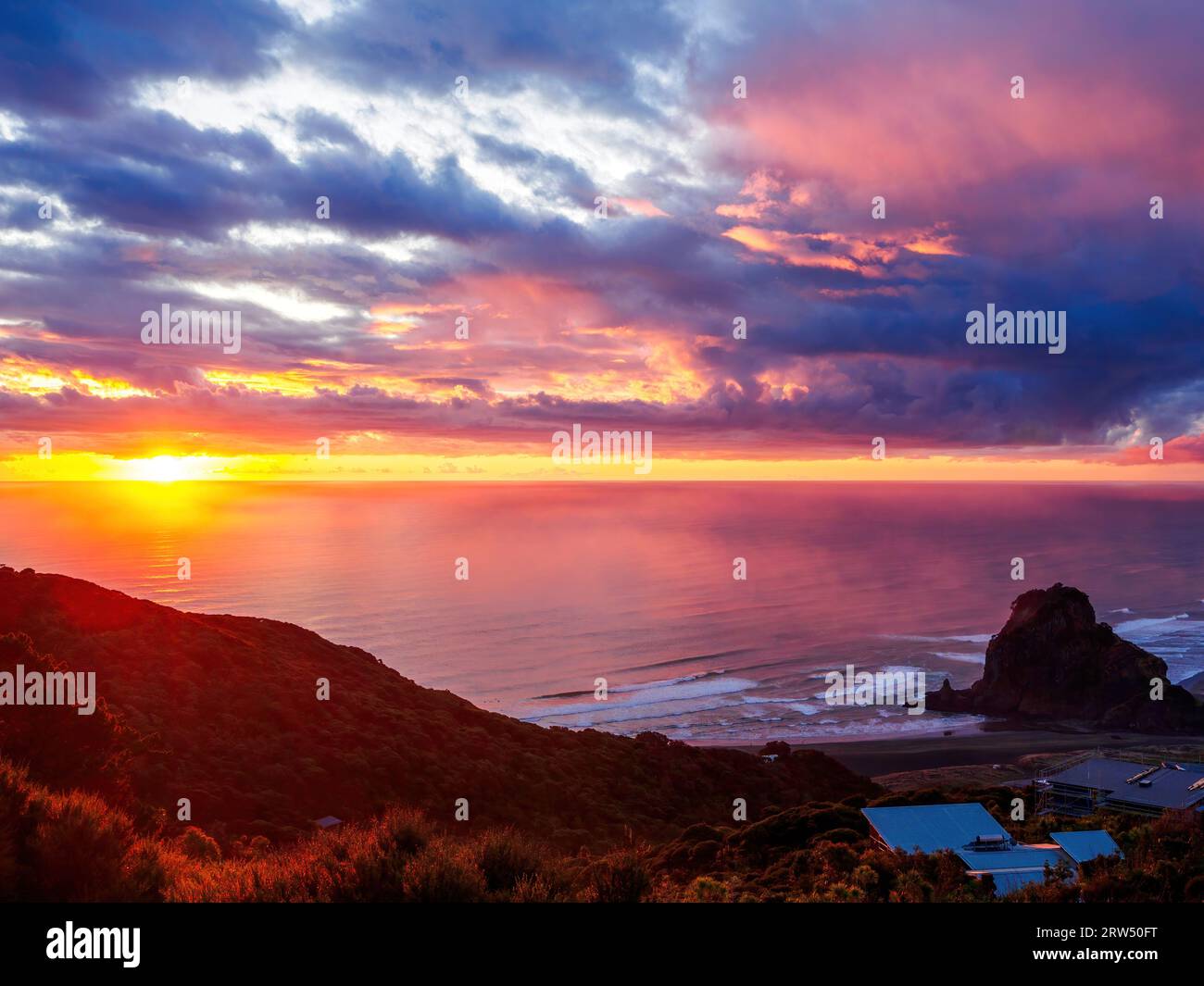 Sunset with dramatic clouds over Tasman sea at Piha beach. View of Lion ...