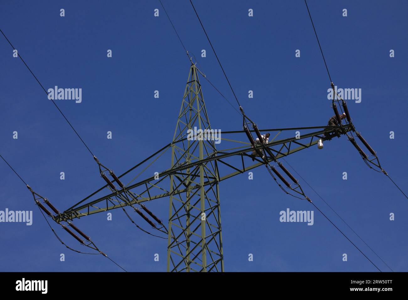 Workers paint high-voltage pylon at lofty heights Stock Photo - Alamy