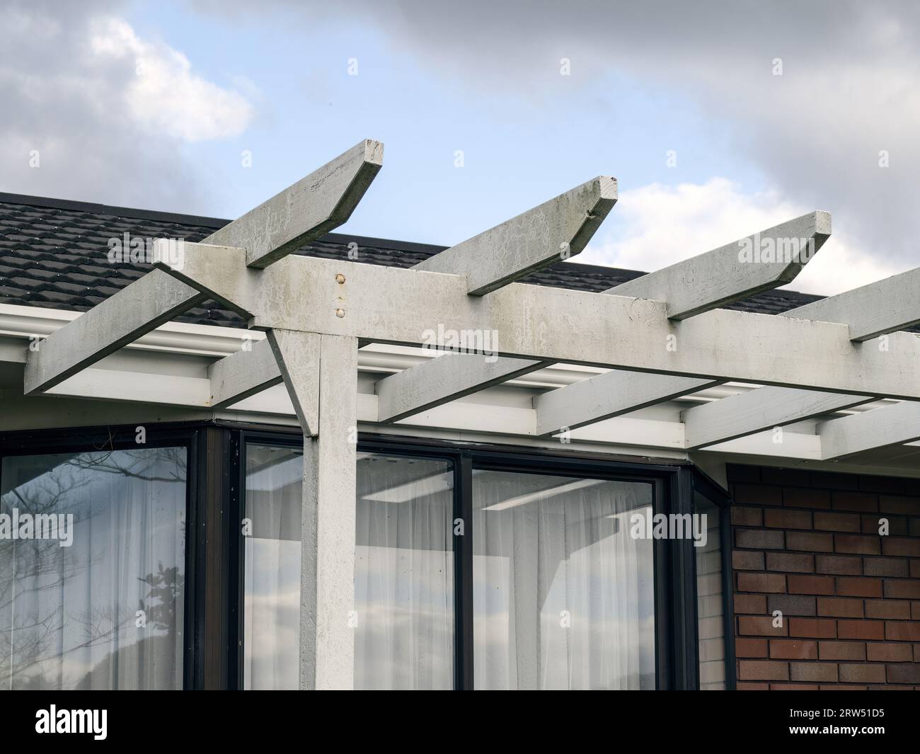 Top part of attached to house wooden white garden pergola. Cross-beams ...