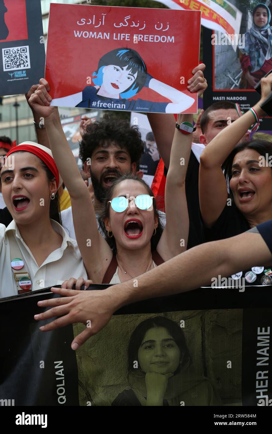 A women with round mirror sunglasses and a ‘Woman Life Freedom' placard ...