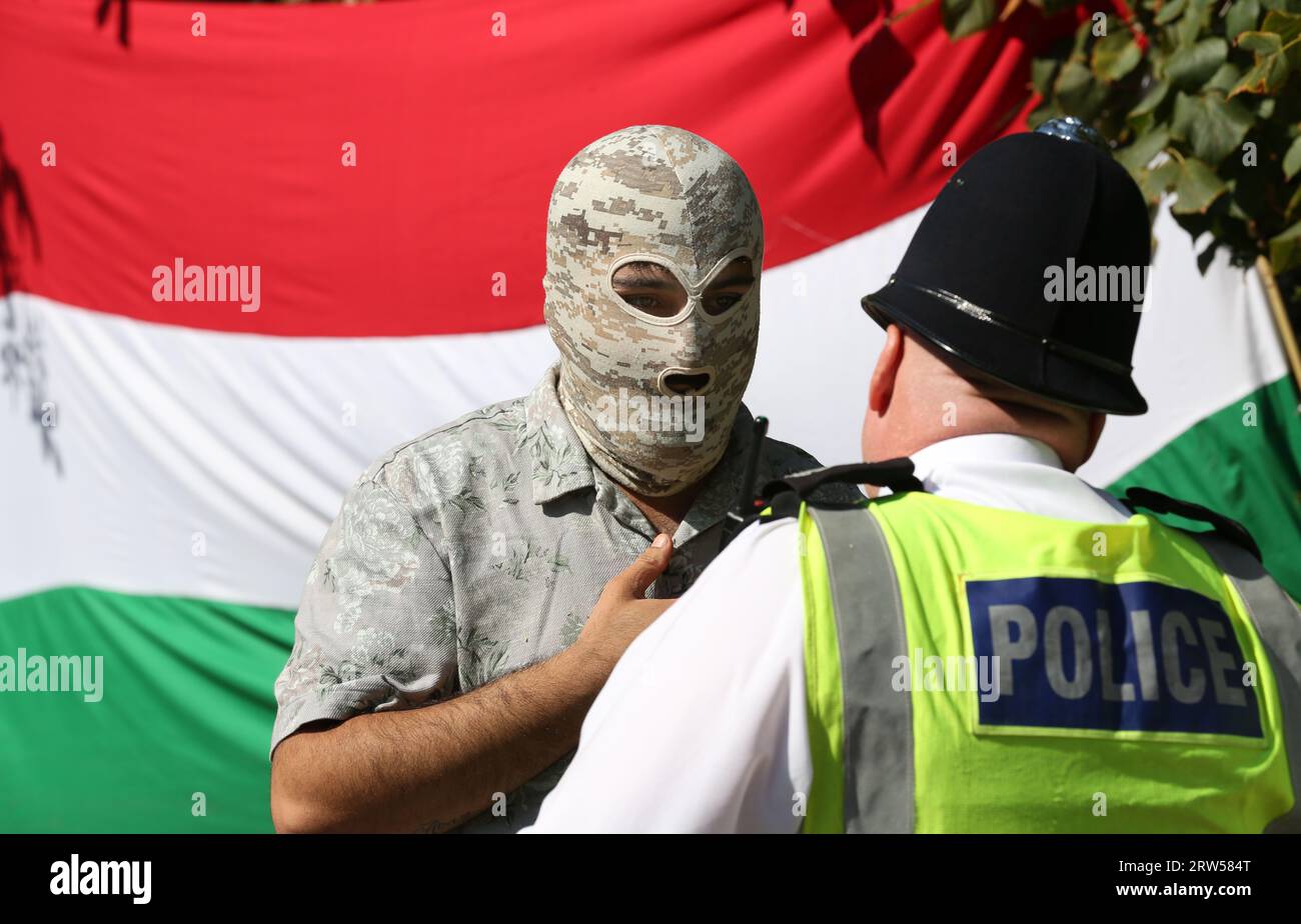 A police officer asks a protester to remove a full face mask outside ...