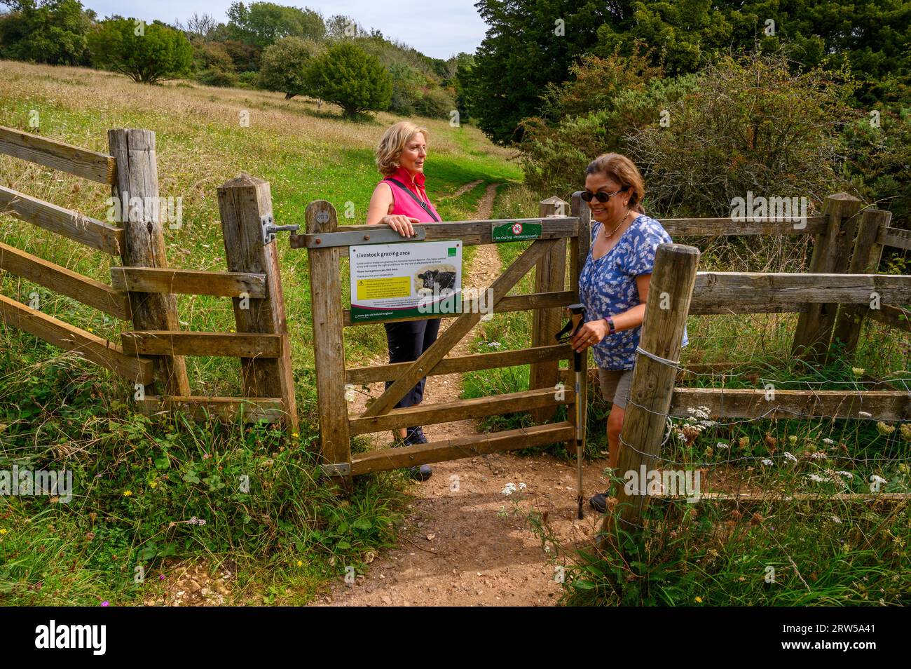 Two middle-aged women walk through a wooden gate on their way up to the ...