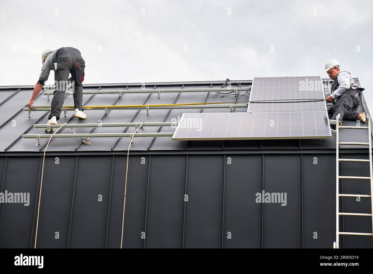 Men measuring photovoltaic solar panels with tape measure. Technicians ...
