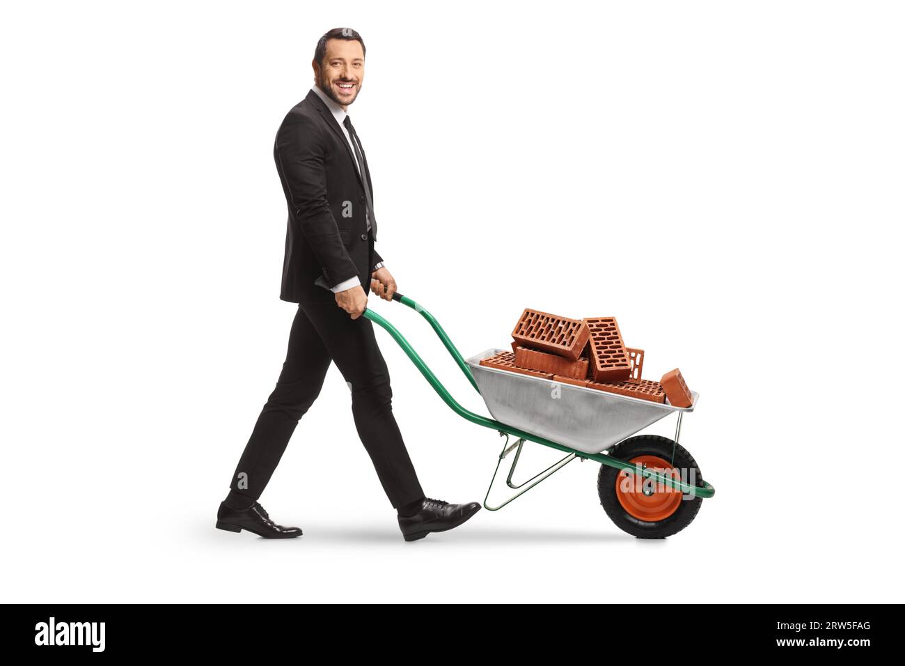 Businessman pushing a wheelbarrow with bricks isolated on white ...
