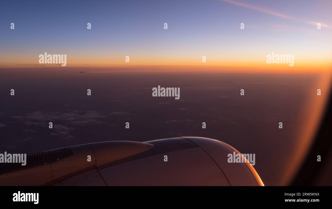 Plane window photo over the clouds with sunset or sunrise light, travel ...