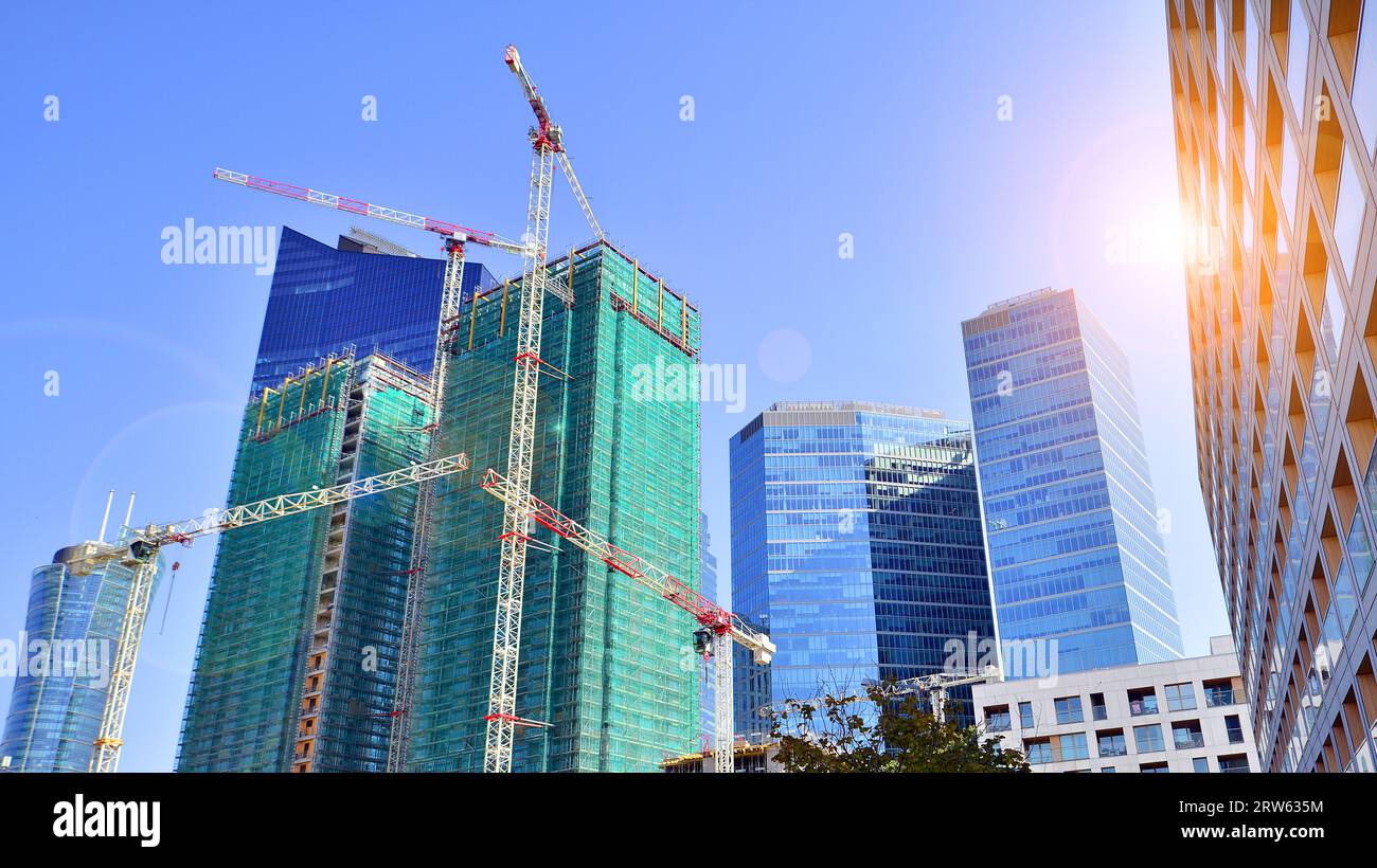 Modern high-rise buildings under construction next to glass skyscrapers ...