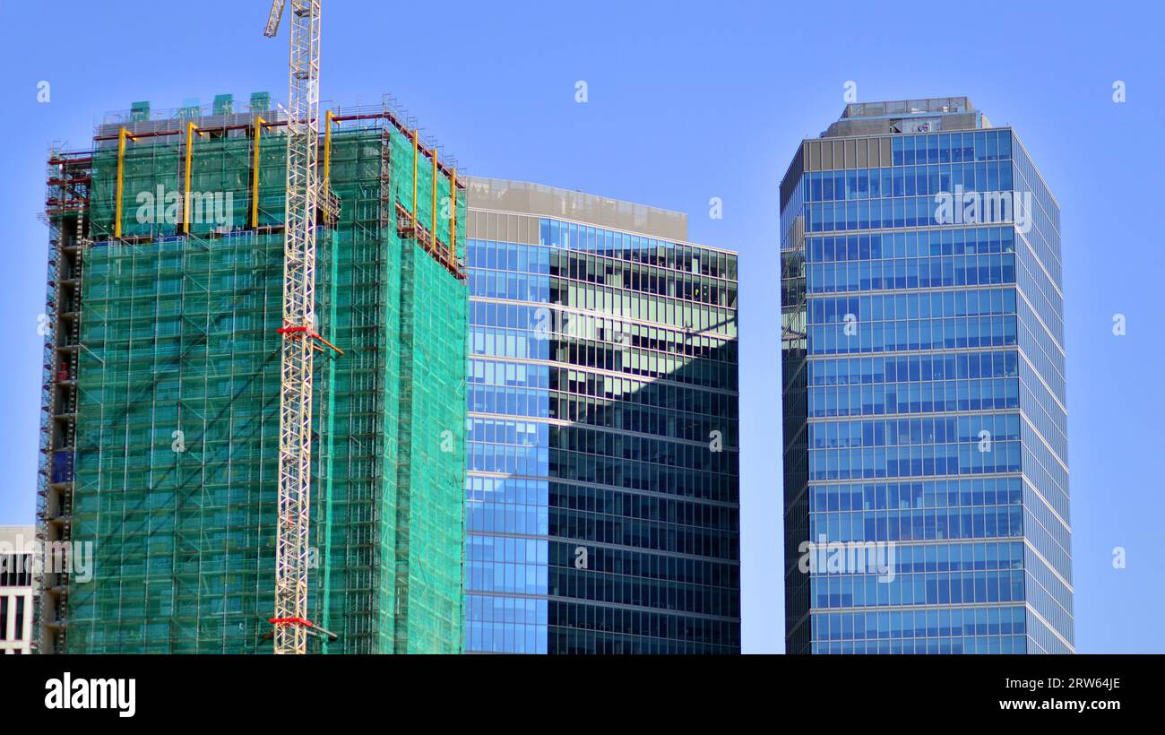Modern high-rise buildings under construction next to glass skyscrapers ...