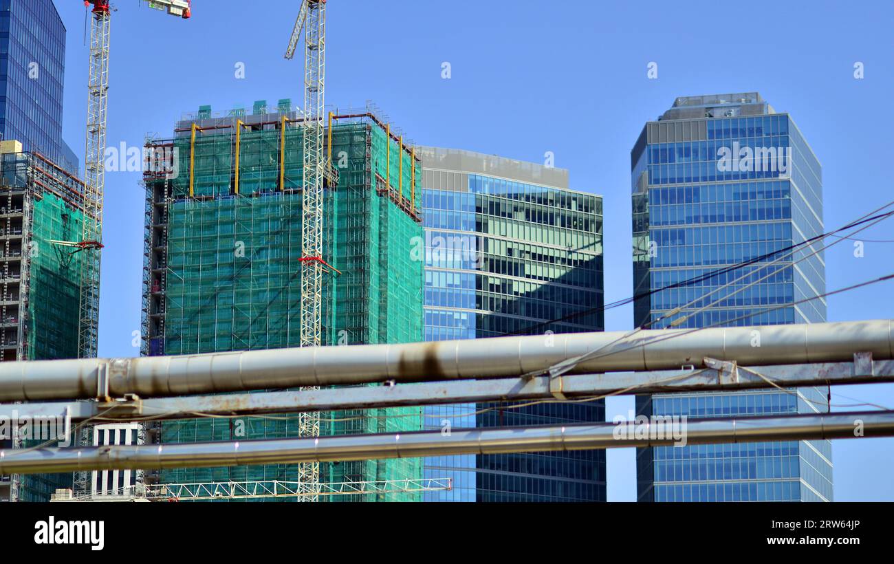Modern high-rise buildings under construction next to glass skyscrapers ...