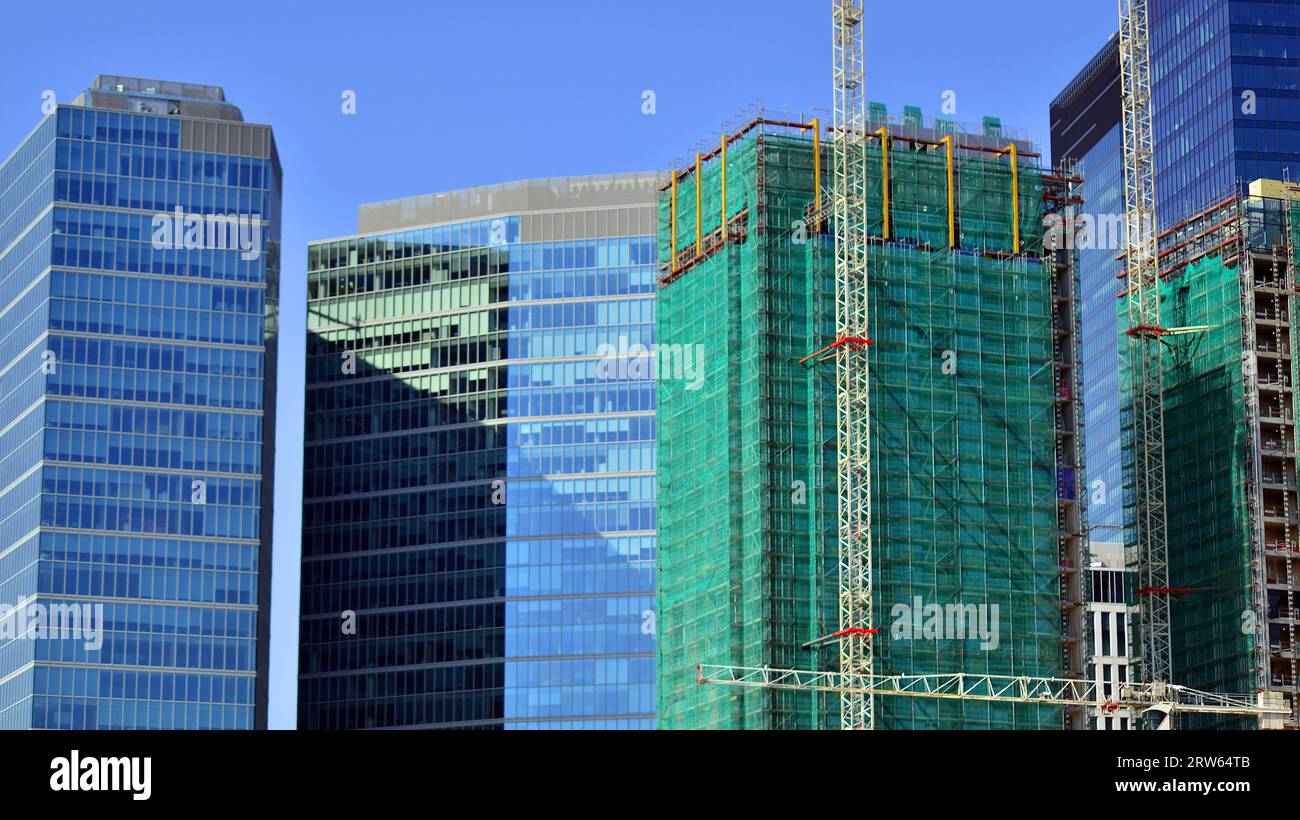 Modern high-rise buildings under construction next to glass skyscrapers ...