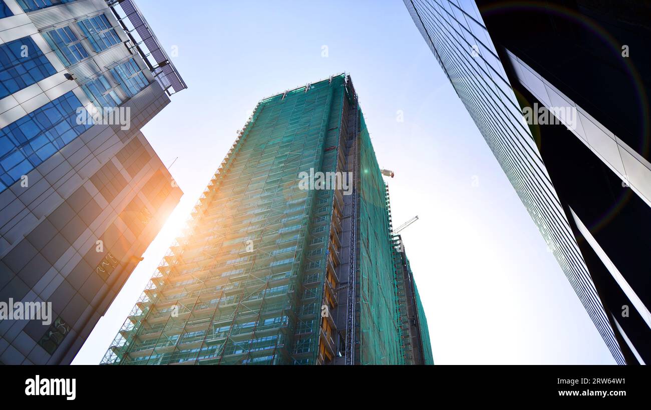 Modern high-rise buildings under construction next to glass skyscrapers ...