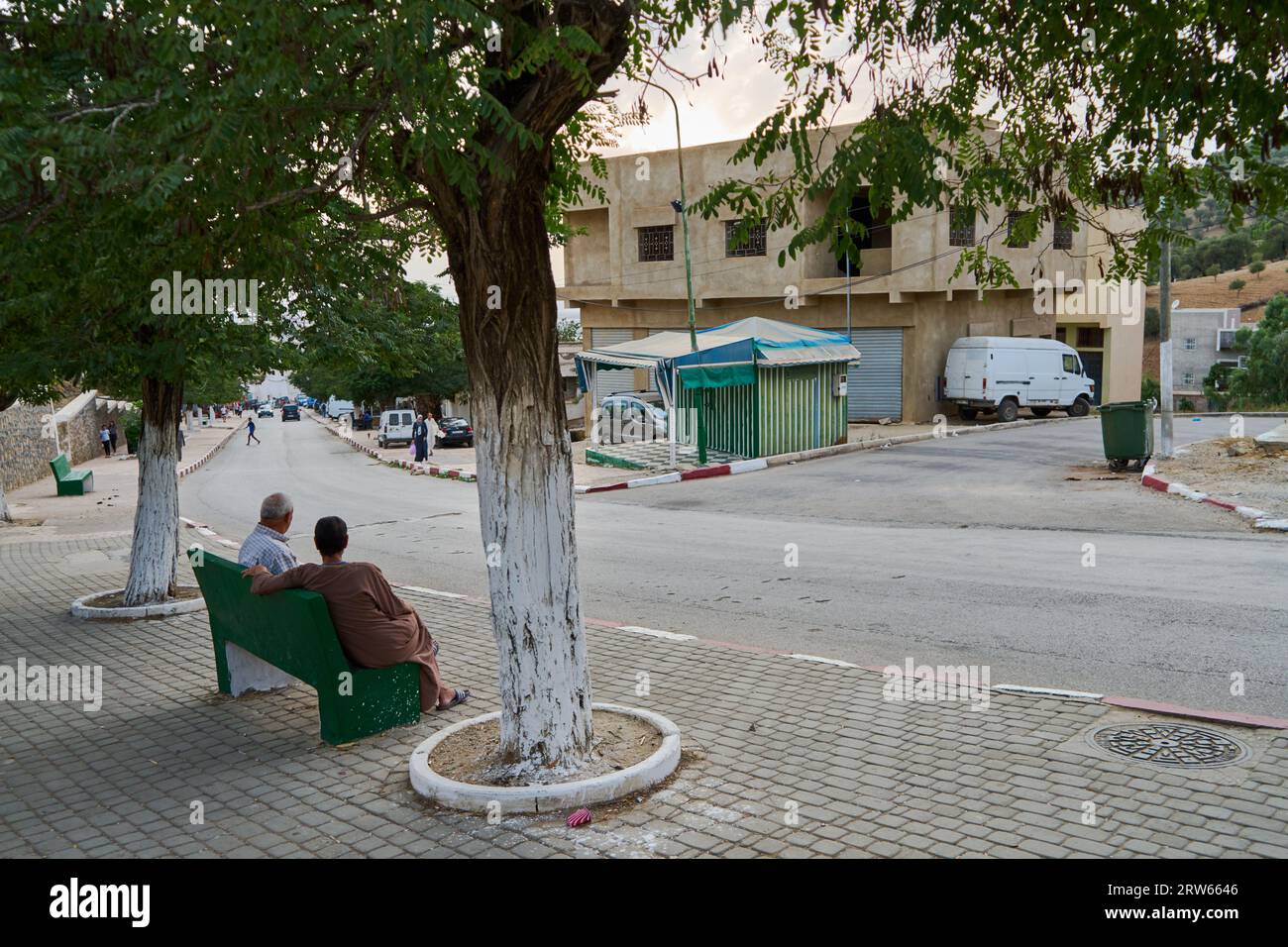 Two men sitting on a bench in the street Stock Photo - Alamy