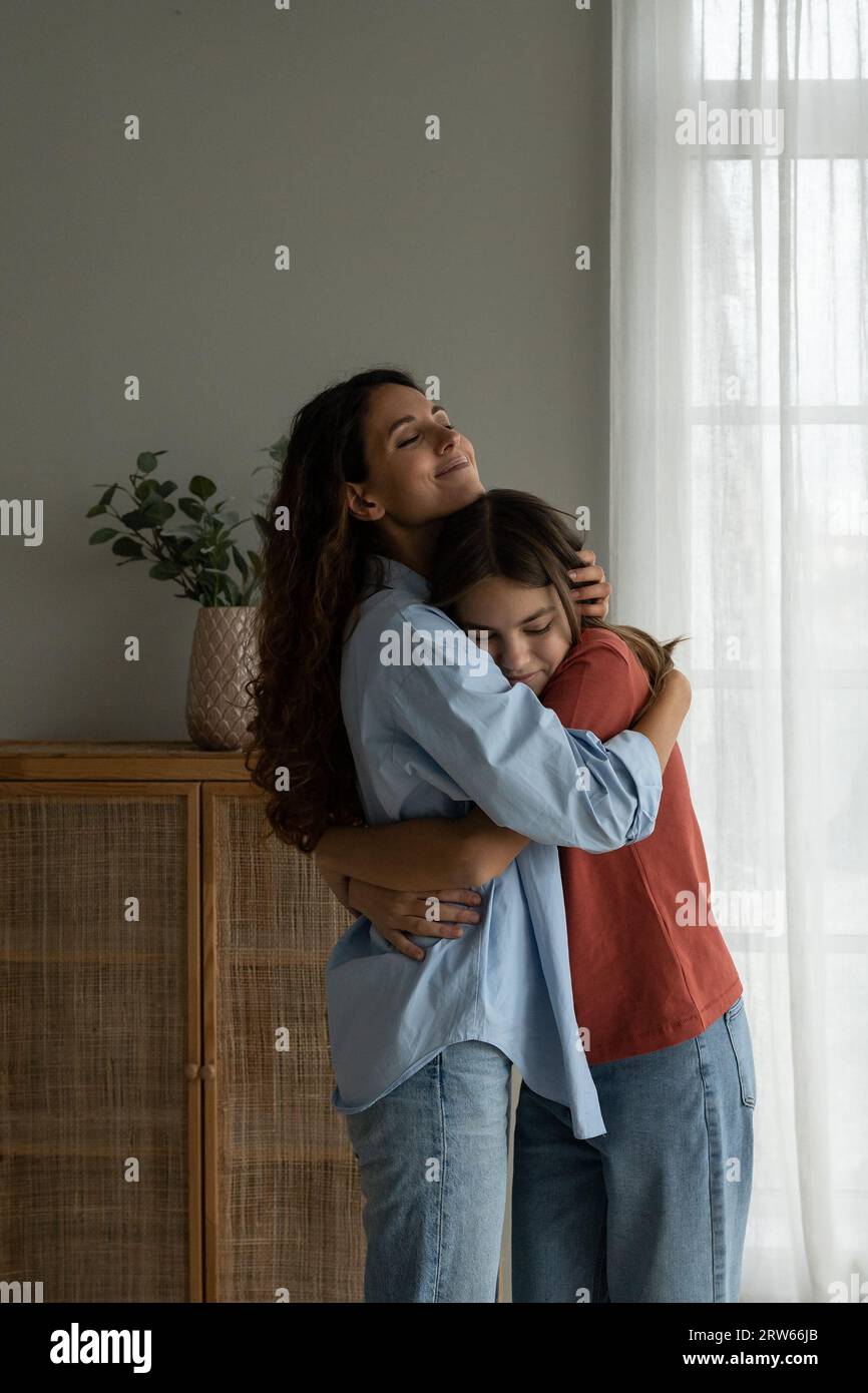 Young loving mother hugging teenage daughter at home, mom cuddling ...