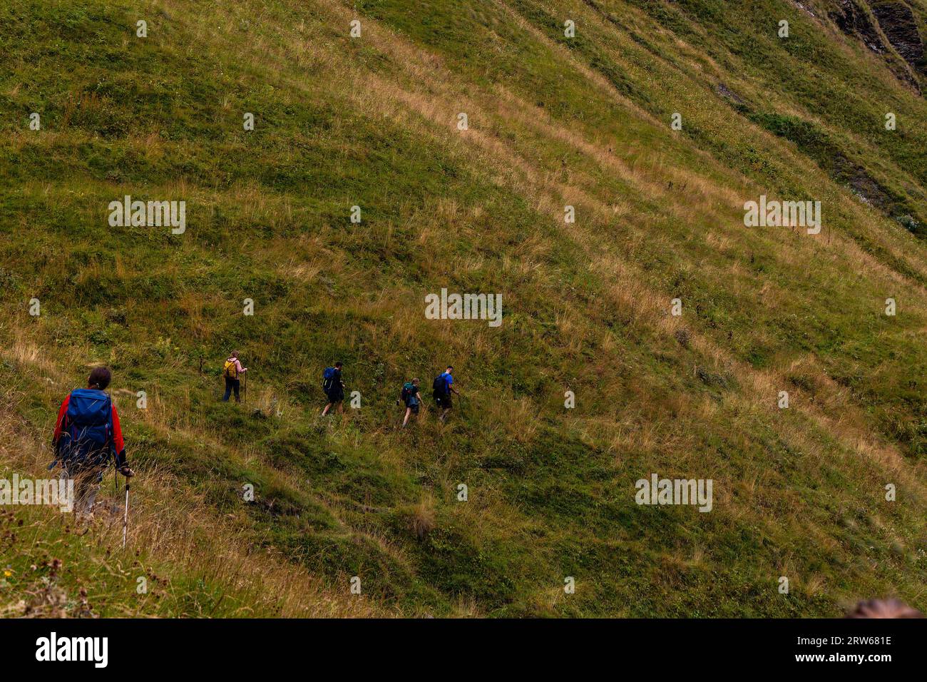 A group of hikers trekking up a steep mountain path, making their way ...