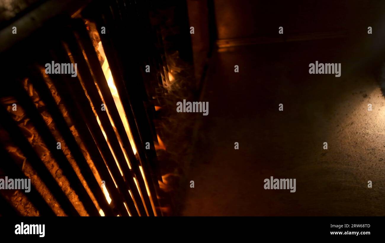 Close-up of rekindling grill. Clip. Bottle of liquid is sprayed onto ...