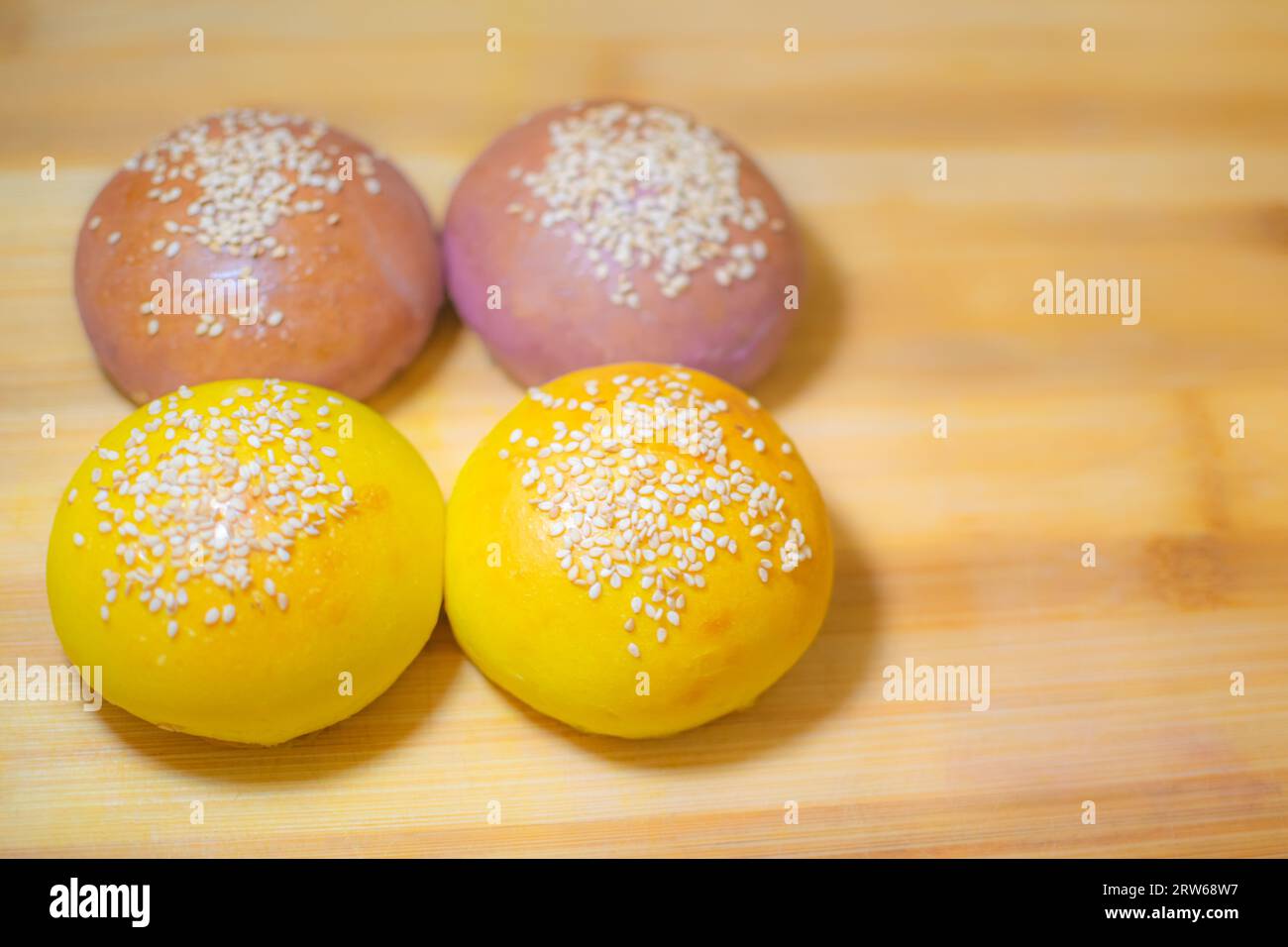 Fun colored artisanal hamburger buns with sesame seeds on wooden ...