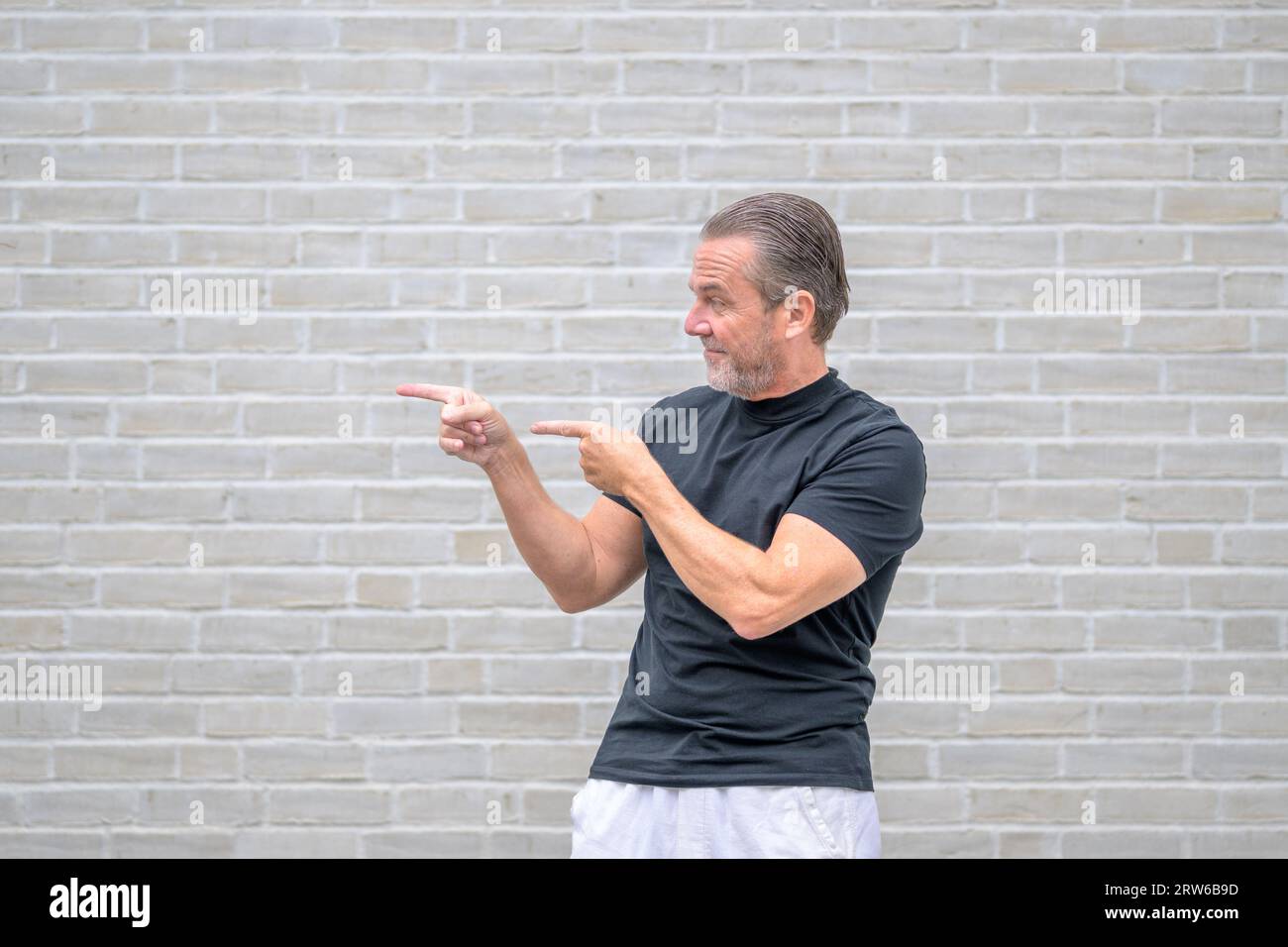 Portrait of an attractive friendly man pointing to the left side and ...