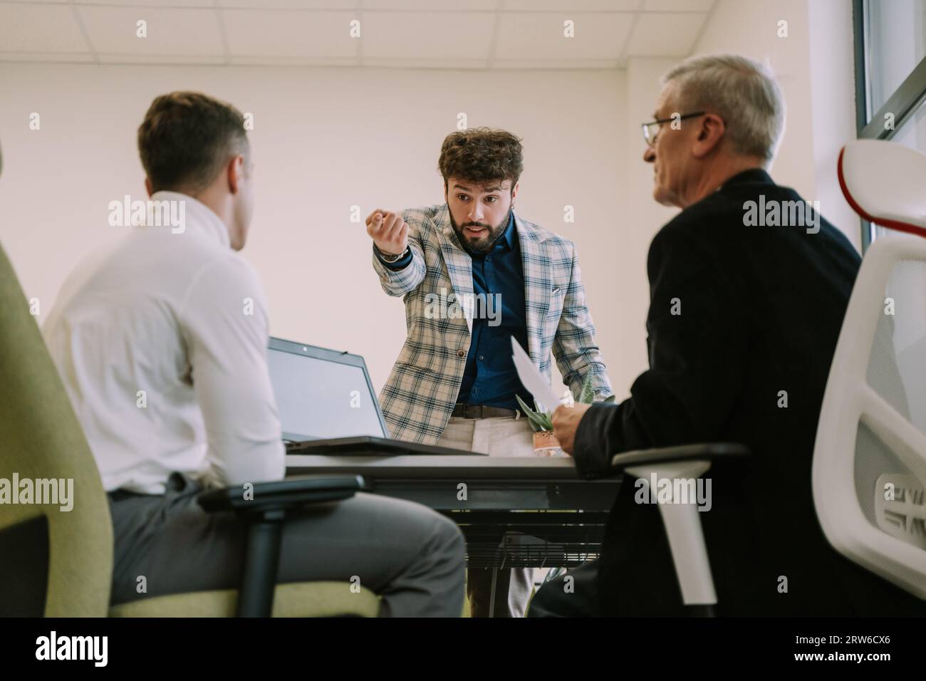 Disappointed and angry boss overlooking and correcting his employees at ...