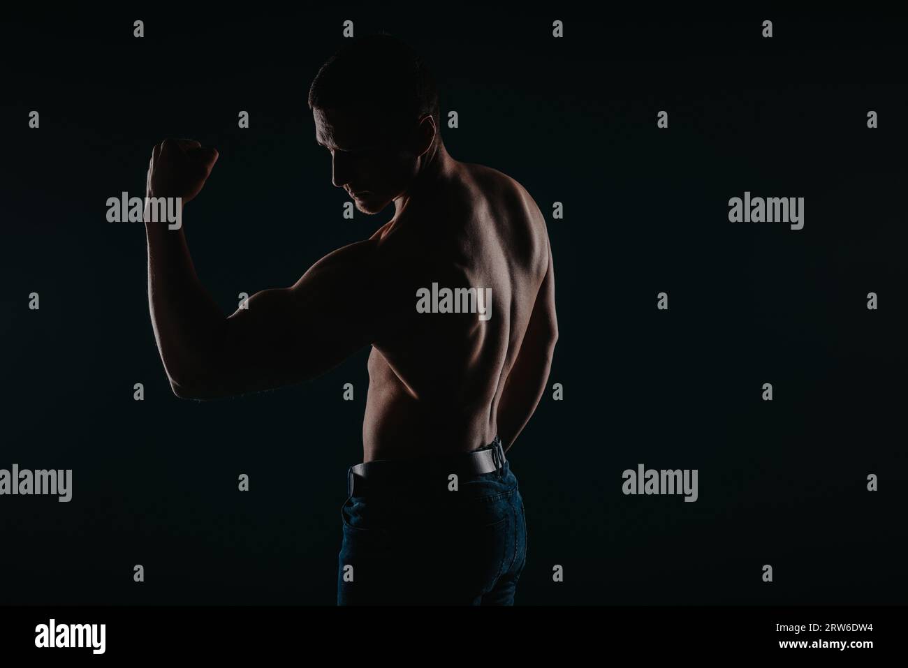 Fit man showing biceps. Strong man looking at his biceps while posing ...